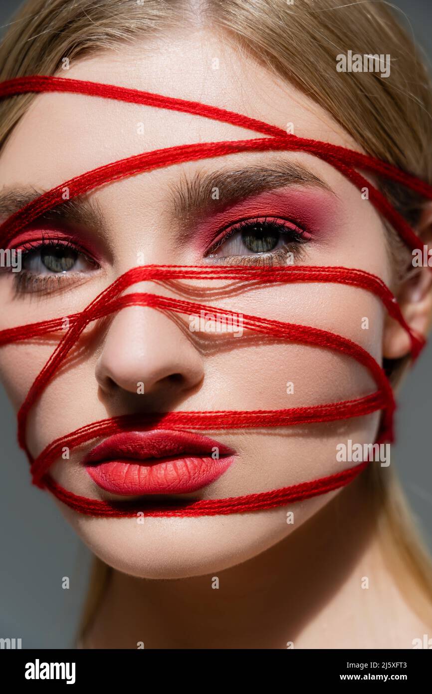 Portrait of young model with lips and threads on face looking at camera ...