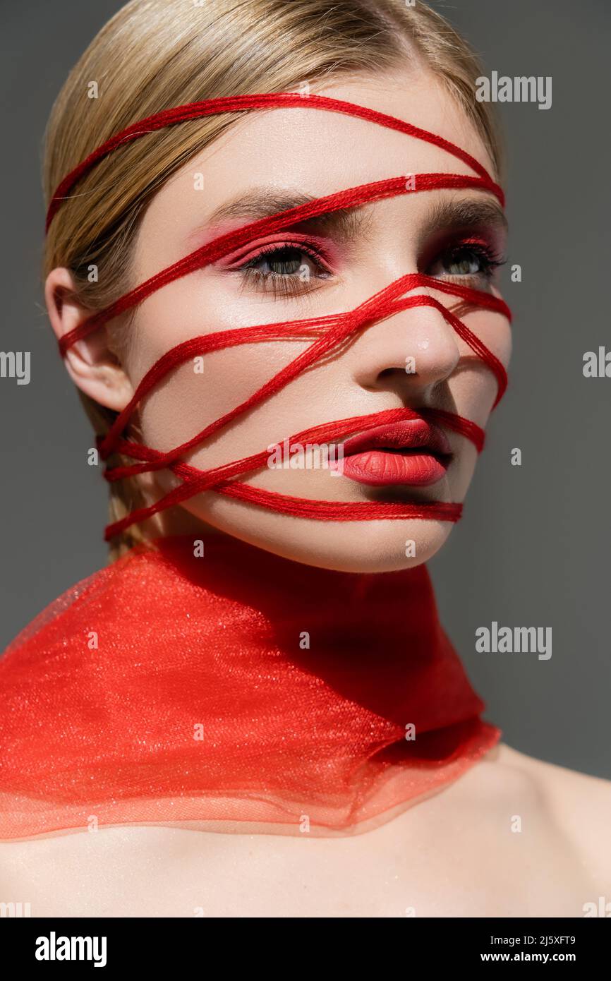 Fair haired model with red threads and visage looking away isolated on ...