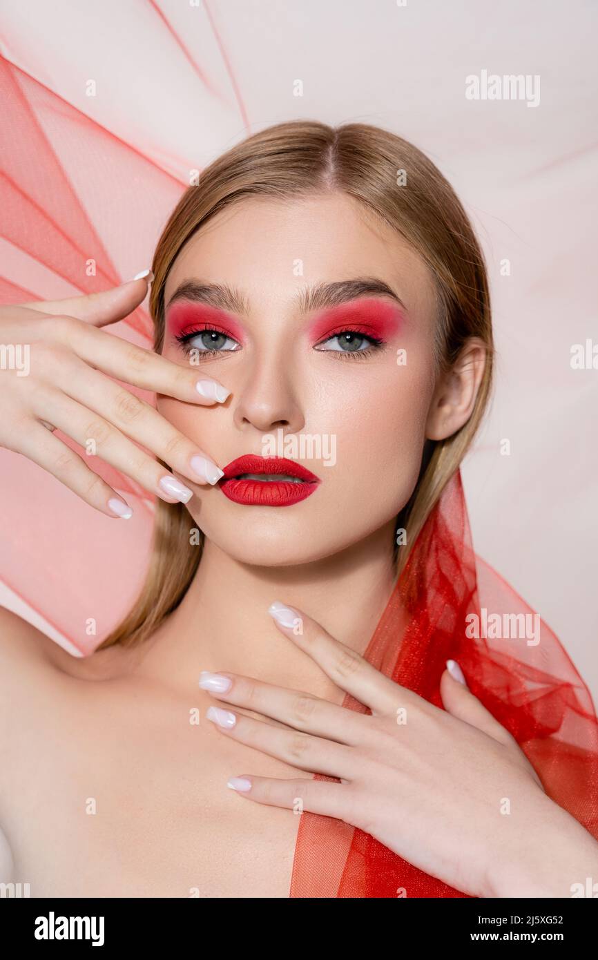Young model with red lips and eye shadow posing with cloth on grey ...