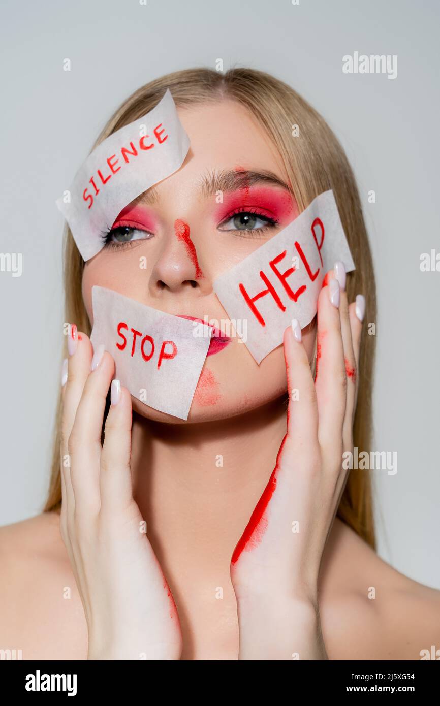 Young woman with paint on hands and papers with silence, stop and help ...