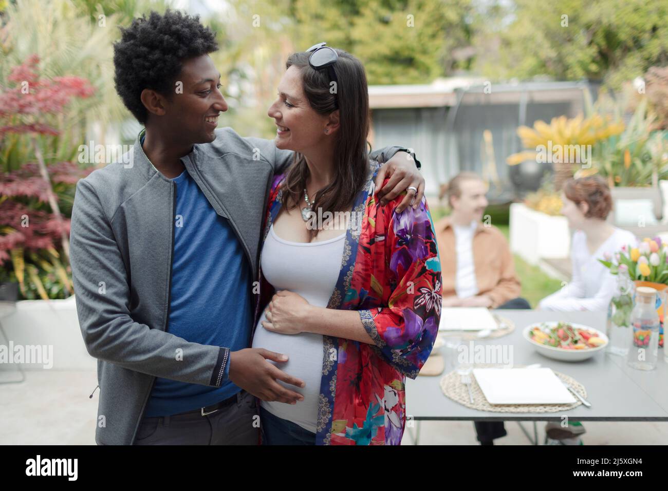 Happy pregnant couple hugging on patio Stock Photo - Alamy
