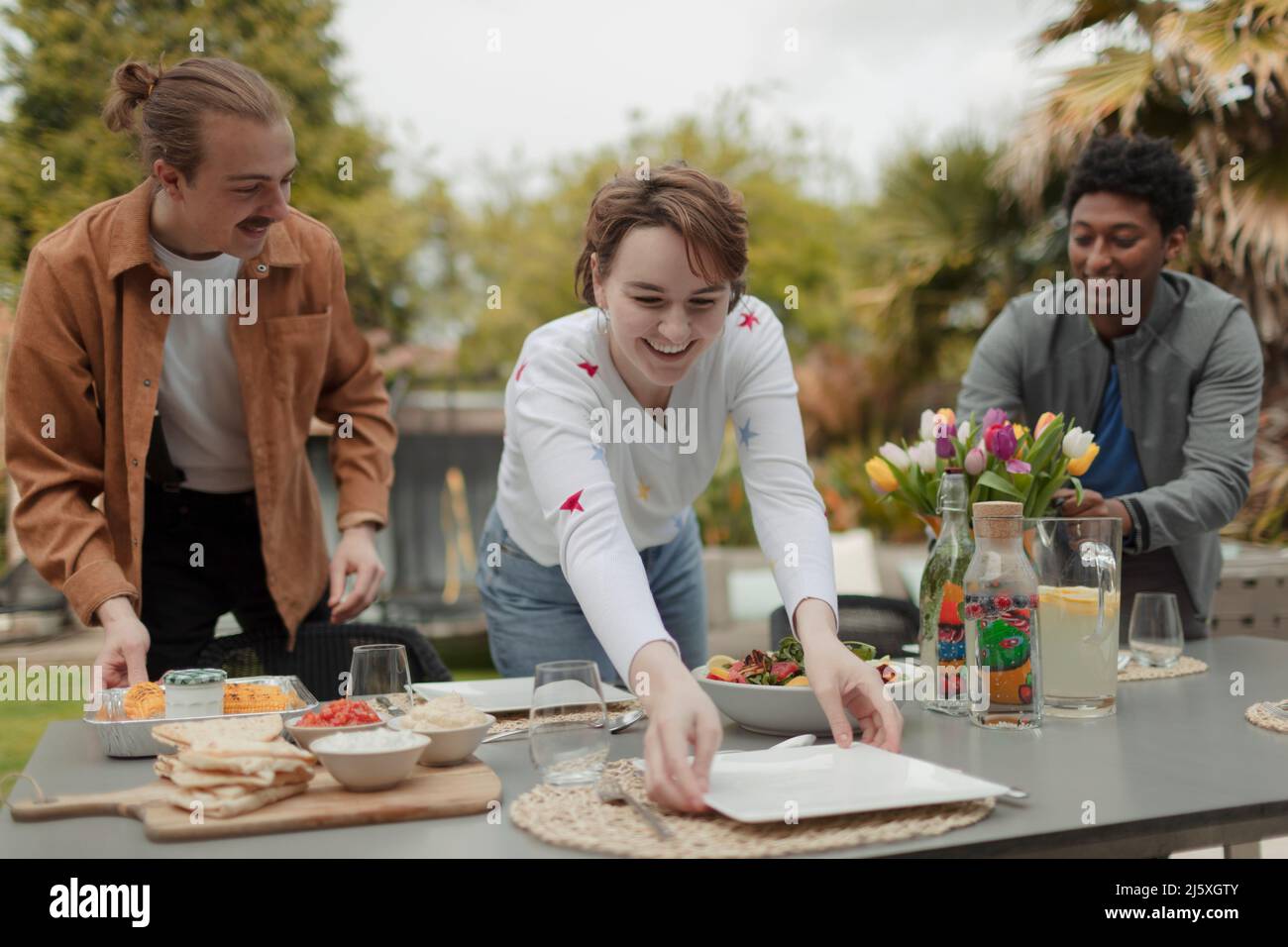 Friends setting patio table for lunch Stock Photo - Alamy