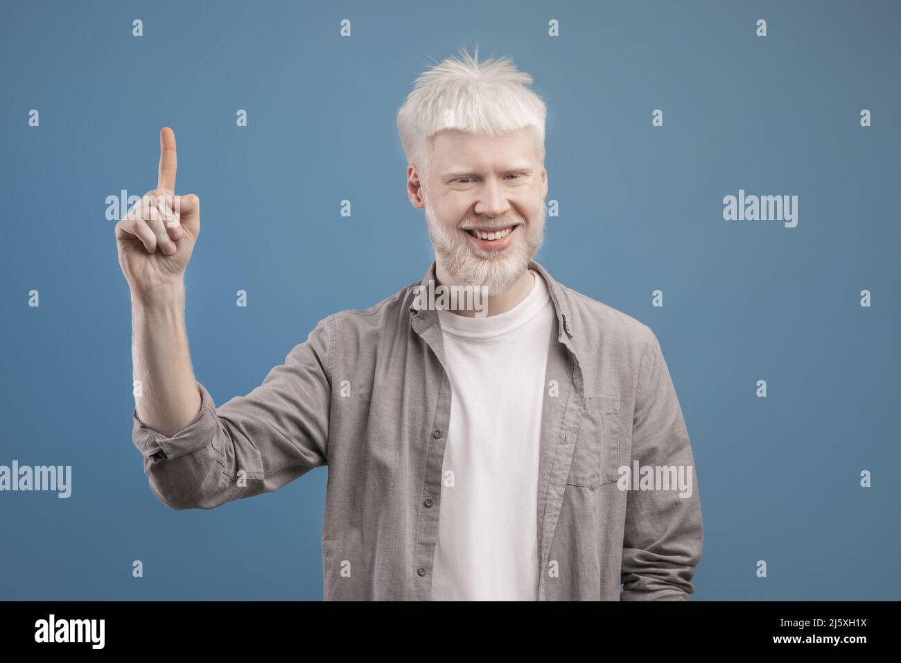 Handsome young albino guy pointing upwards experiencing AHA moment ...
