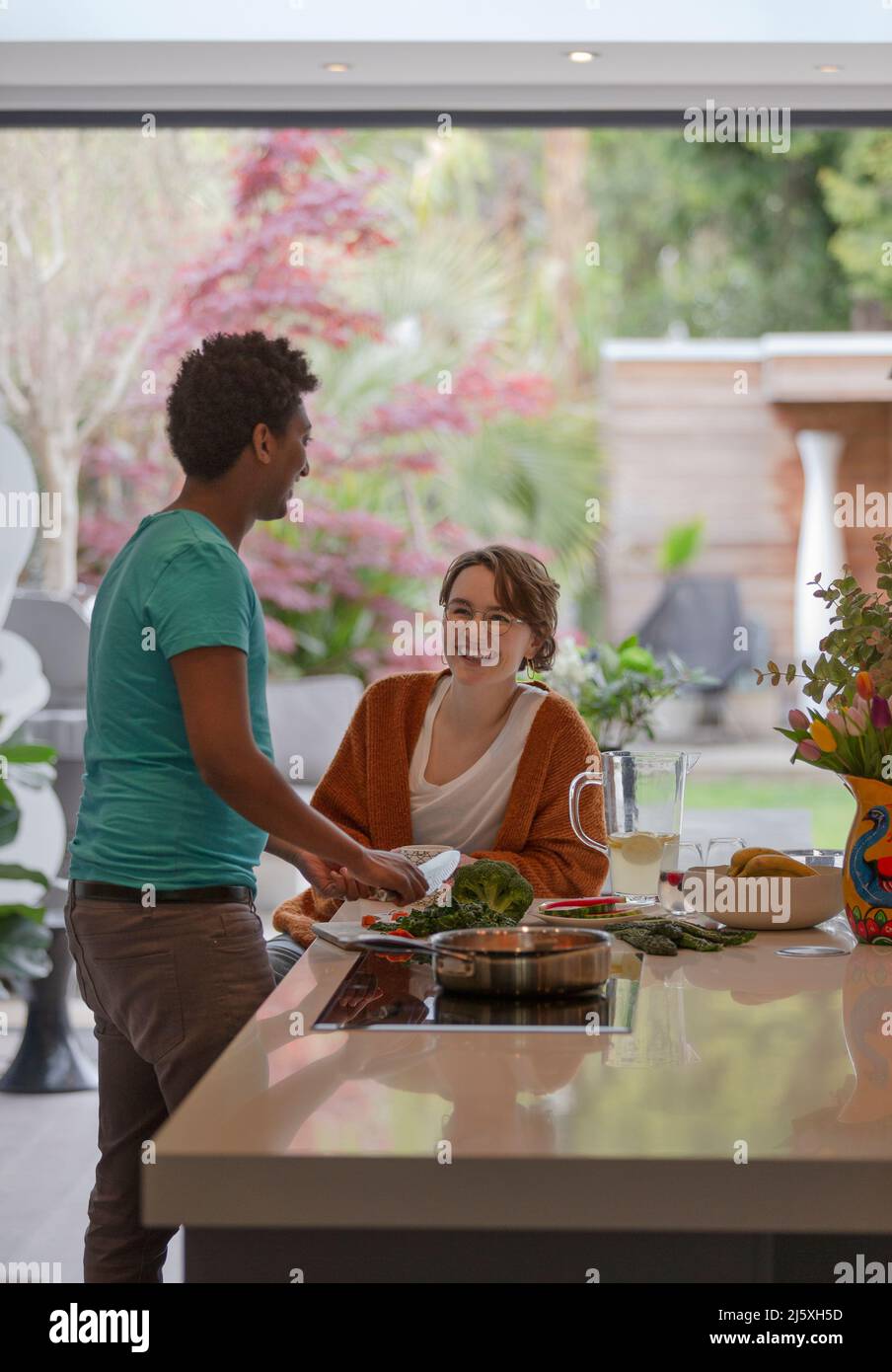 Happy couple talking and cooking in kitchen Stock Photo - Alamy