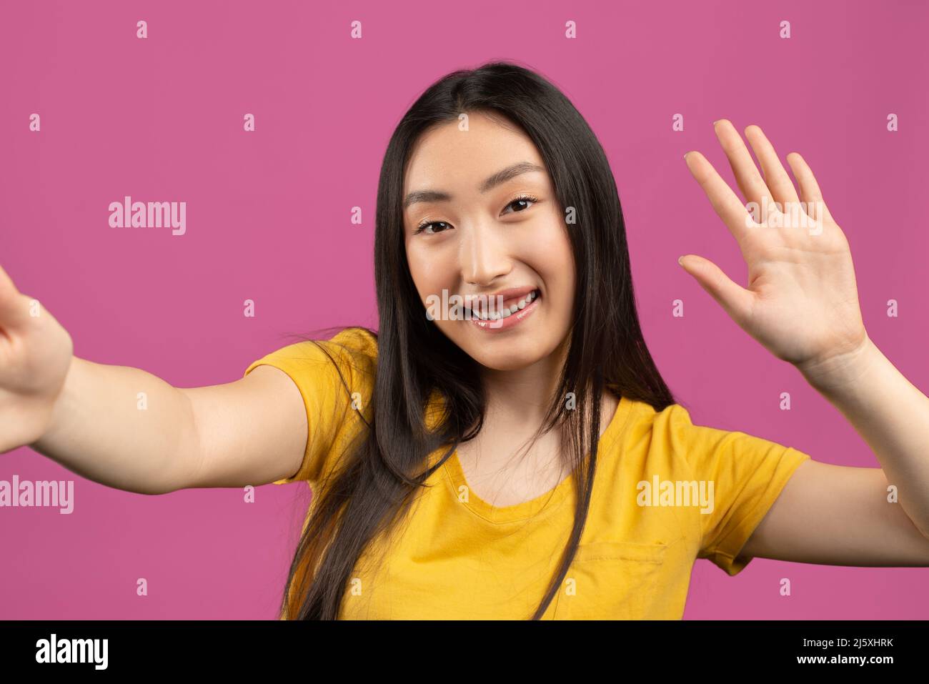 Hello. Happy korean lady taking selfie and waving hand at camera ...