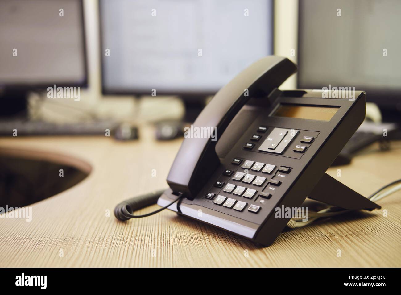 Landline phone on office desk with computer monitors and keyboards ...