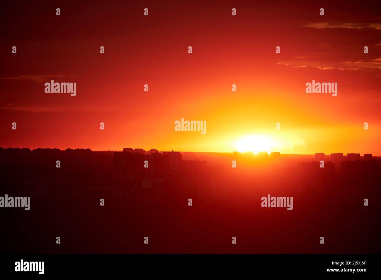Sunset on a red sky with evening clouds in the city. The setting ...