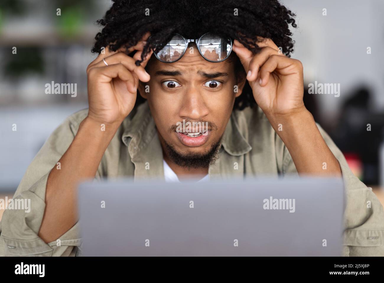 Shocked Millennial African American Curly Male Takes Off Glasses And