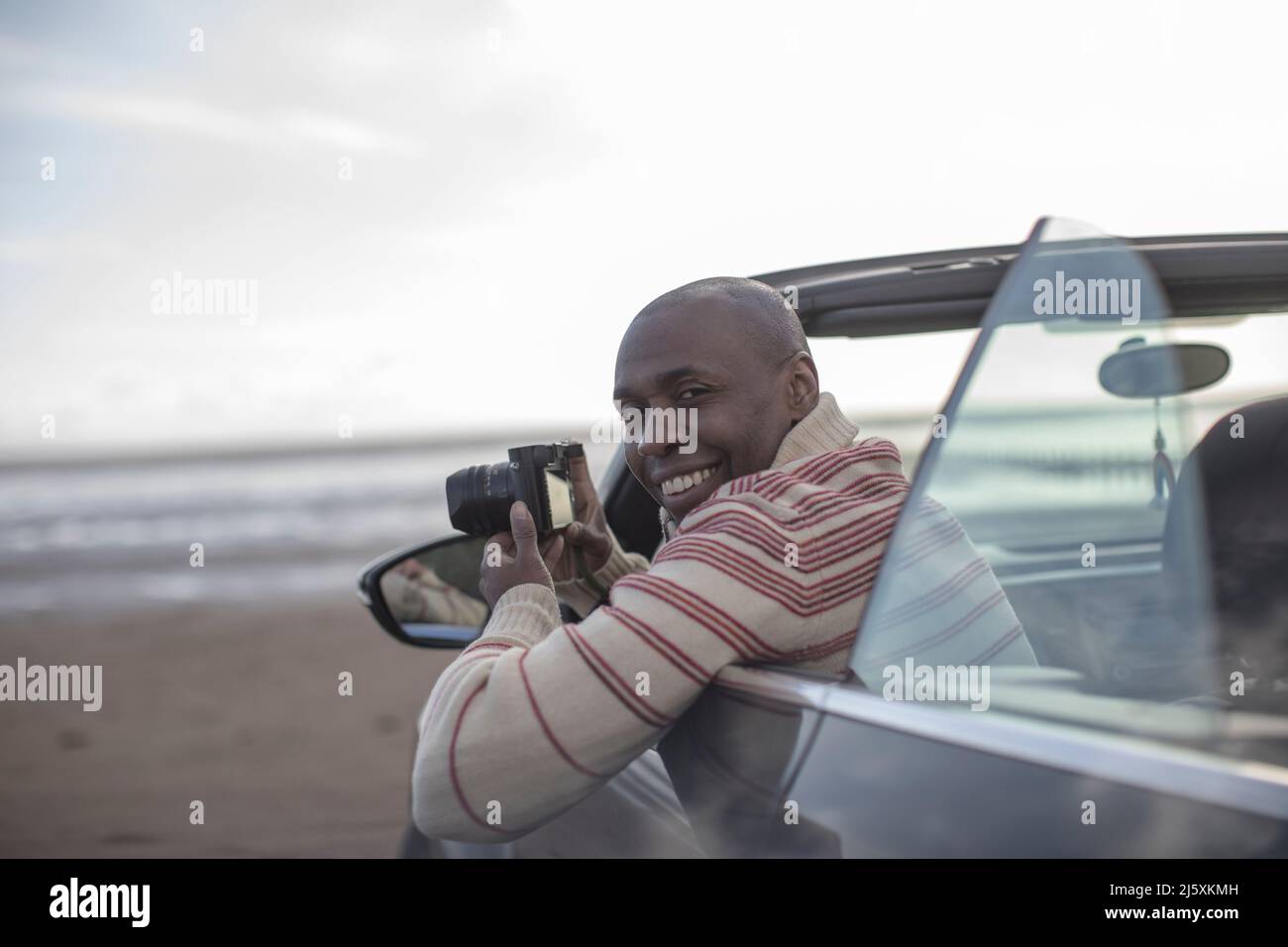 Portrait happy man with digital camera in convertible on beach Stock ...