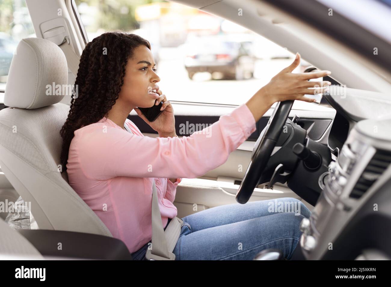 Angry black woman talking on cell phone while driving car Stock Photo ...