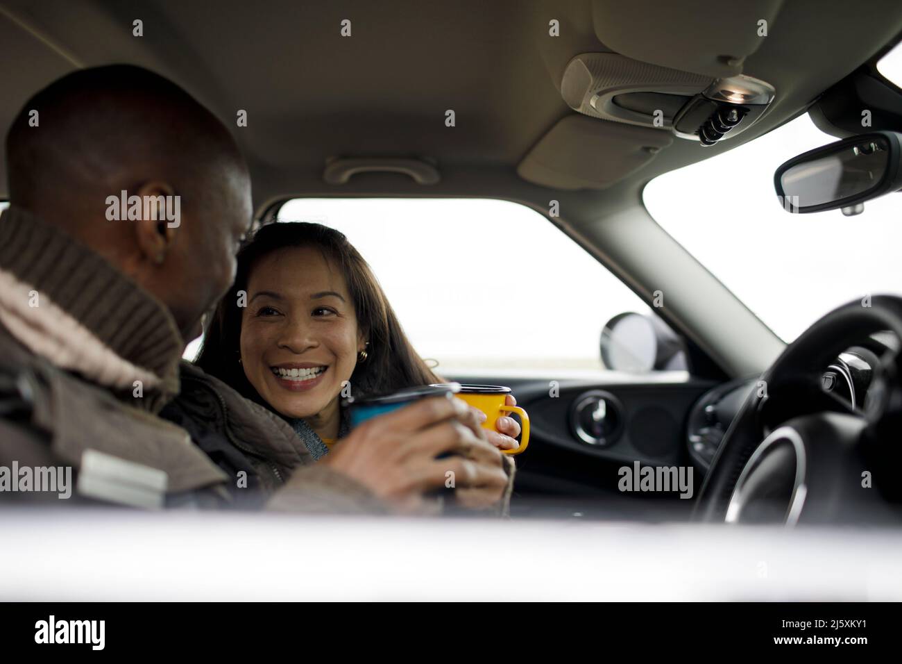 Happy couple drinking coffee inside car Stock Photo - Alamy
