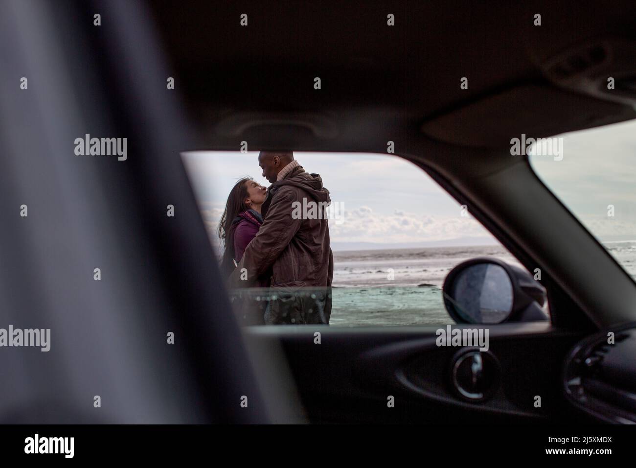 Affectionate couple hugging outside car on beach Stock Photo - Alamy