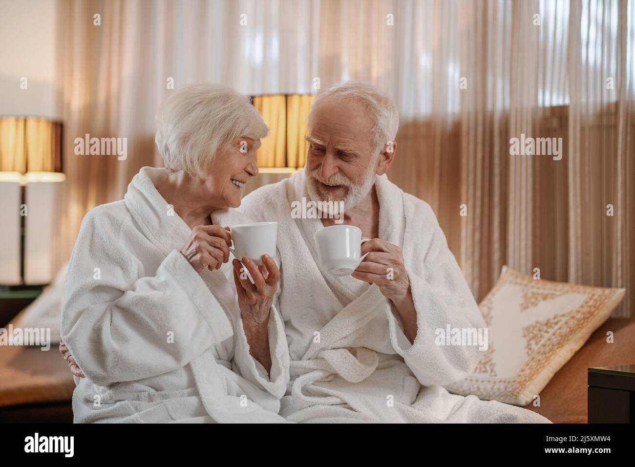 A senior couple in white robes having coffee and talking Stock Photo ...