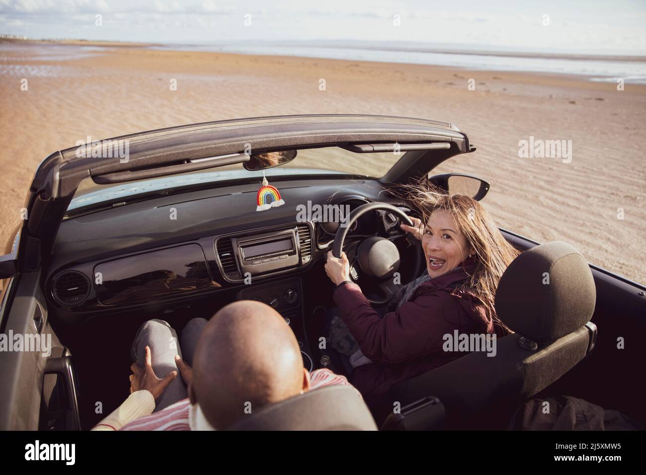 Portrait happy couple driving convertible on sunny beach Stock Photo ...