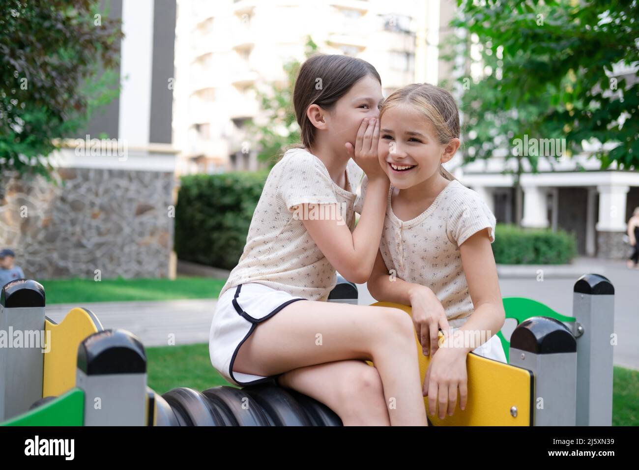 two pretty teen girls playing on a modern playground in identical ...