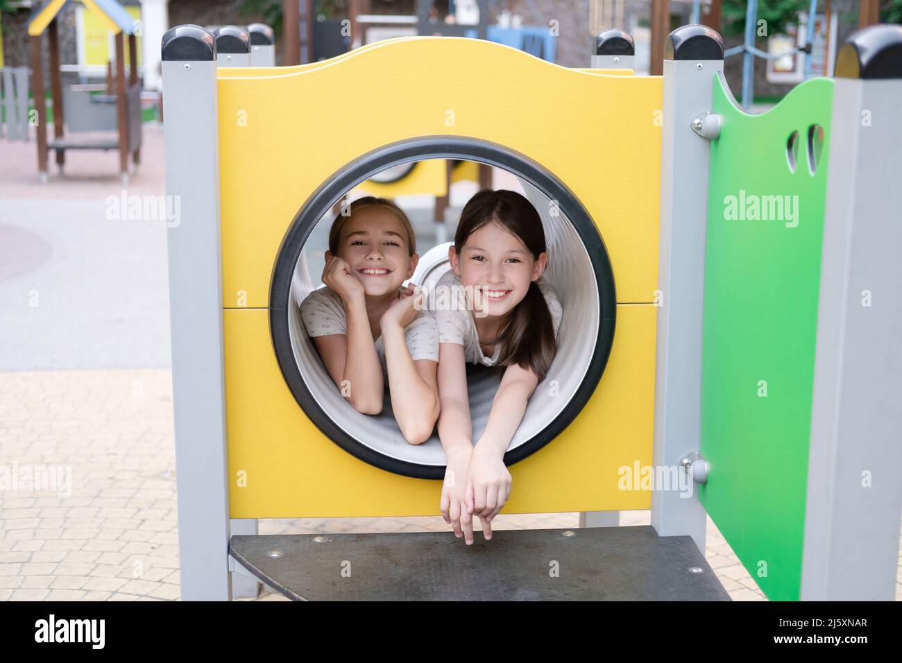 two pretty teen girls playing on a modern playground in identical ...