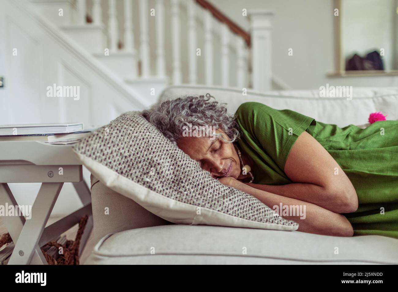 Serene senior woman napping on living room sofa Stock Photo - Alamy