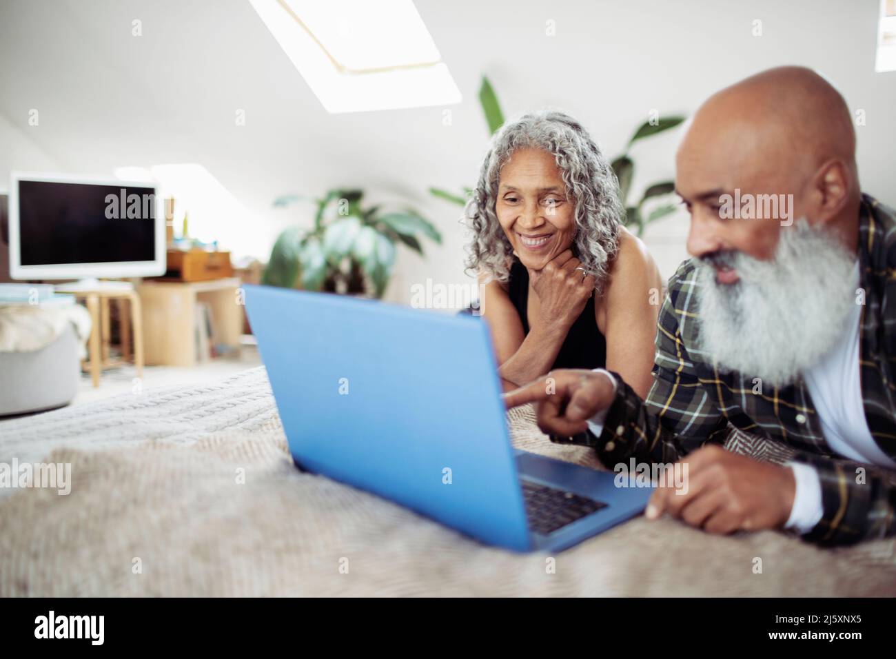 Happy senior couple using laptop on bed Stock Photo - Alamy