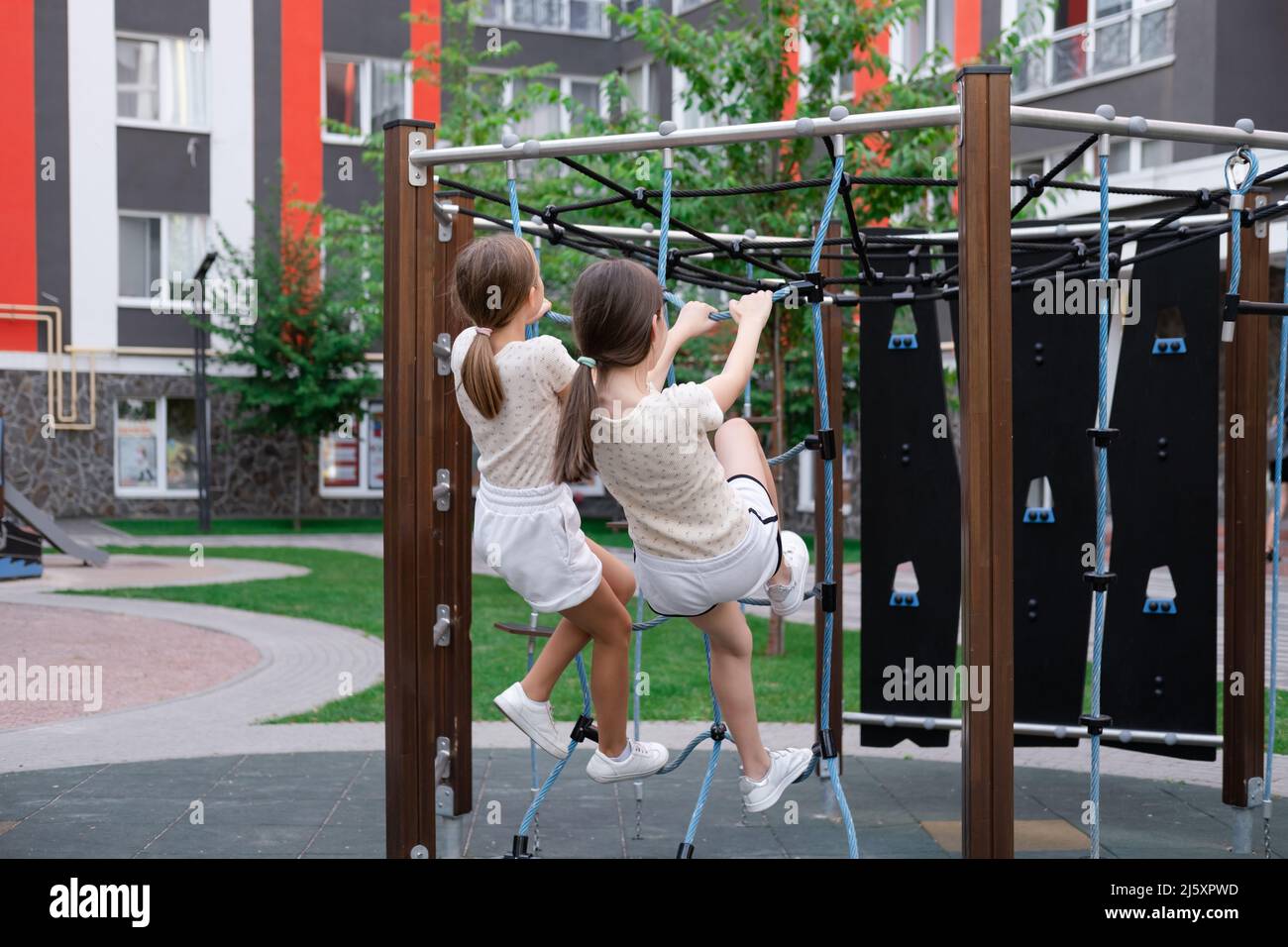 two pretty teen girls playing on a modern playground in identical ...