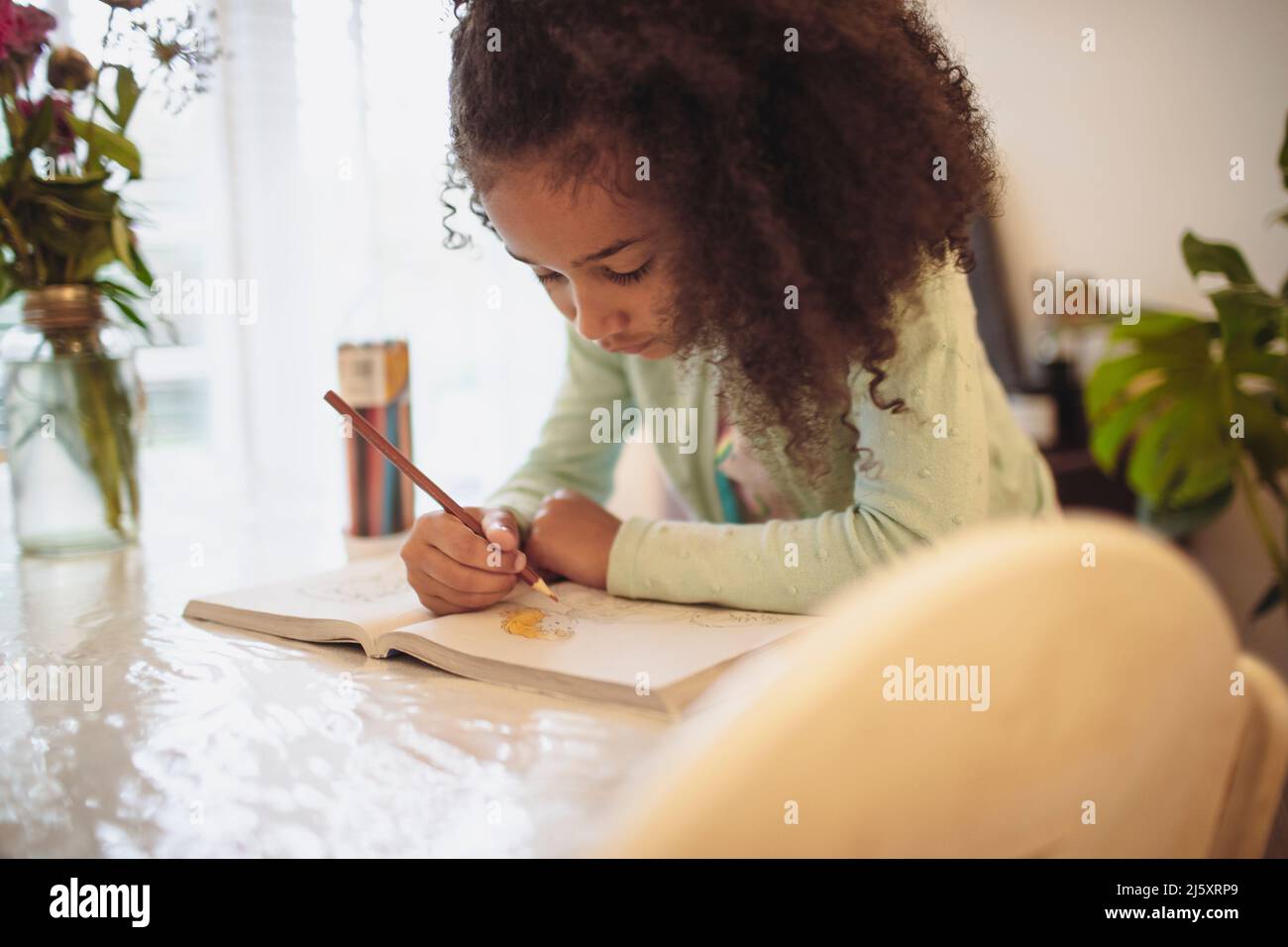 Girl coloring in coloring book at table Stock Photo - Alamy