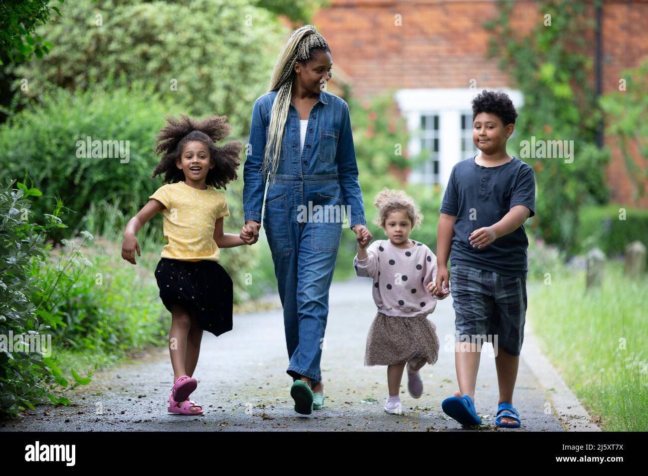Mother and kids holding hands and walking on driveway Stock Photo - Alamy