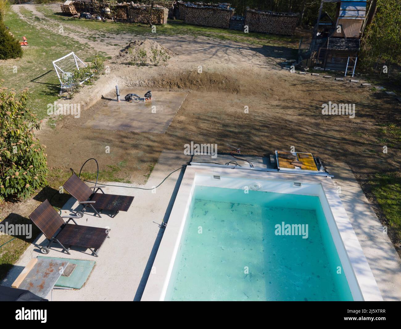 Drone flight over fresh earth area with grass grown next to pool ...