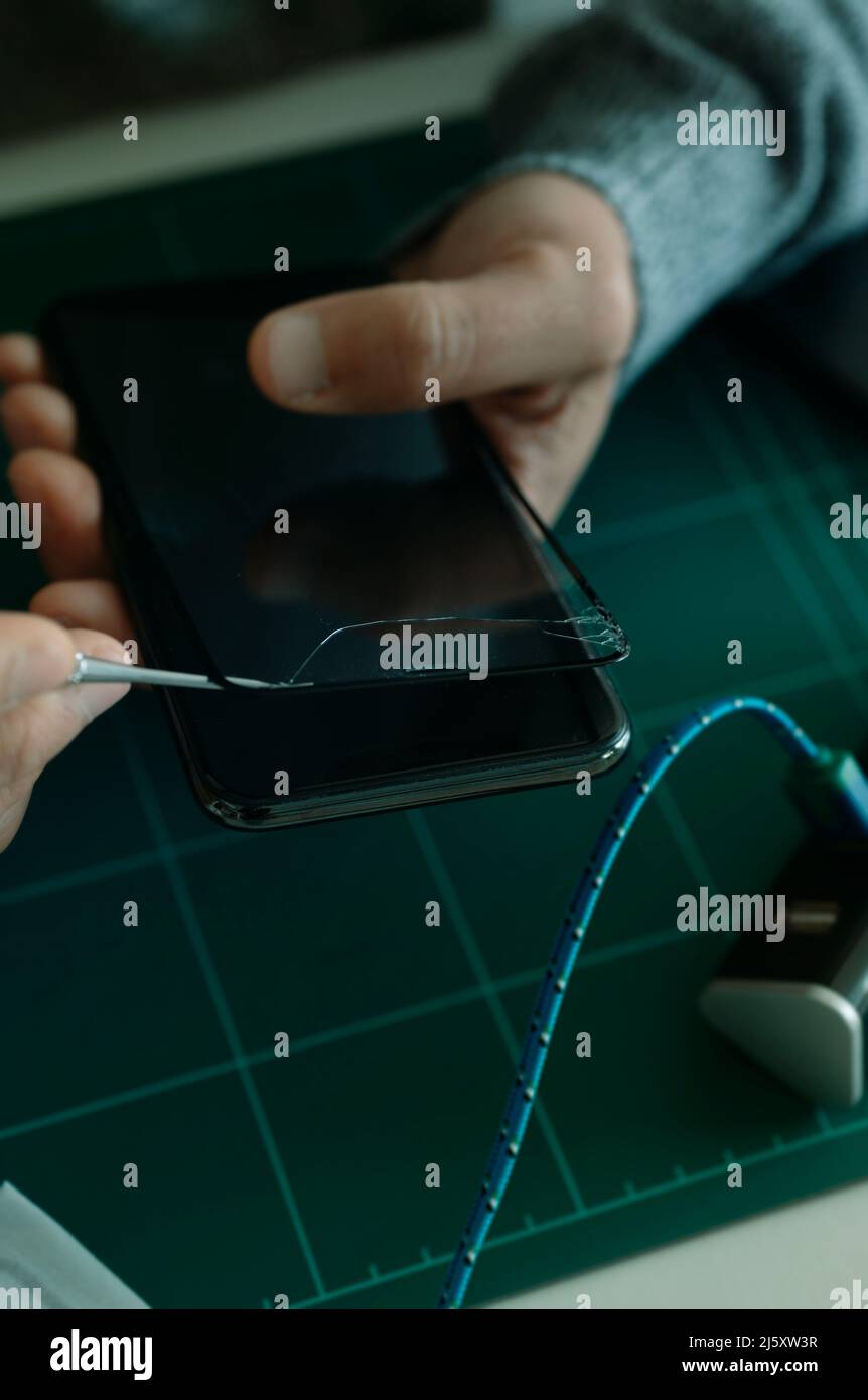 a young caucasian man removes the broken screen protector of a ...