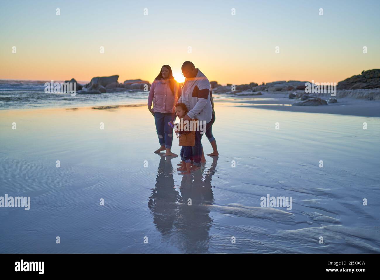Family wading in wet sand on ocean beach at sunset Stock Photo - Alamy