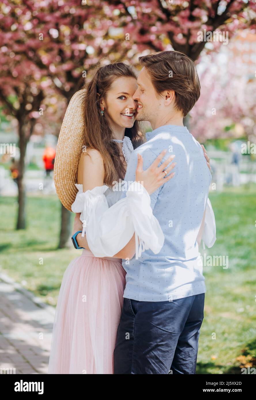 Young couple hugging in the park. Alley with sakura trees Stock Photo ...