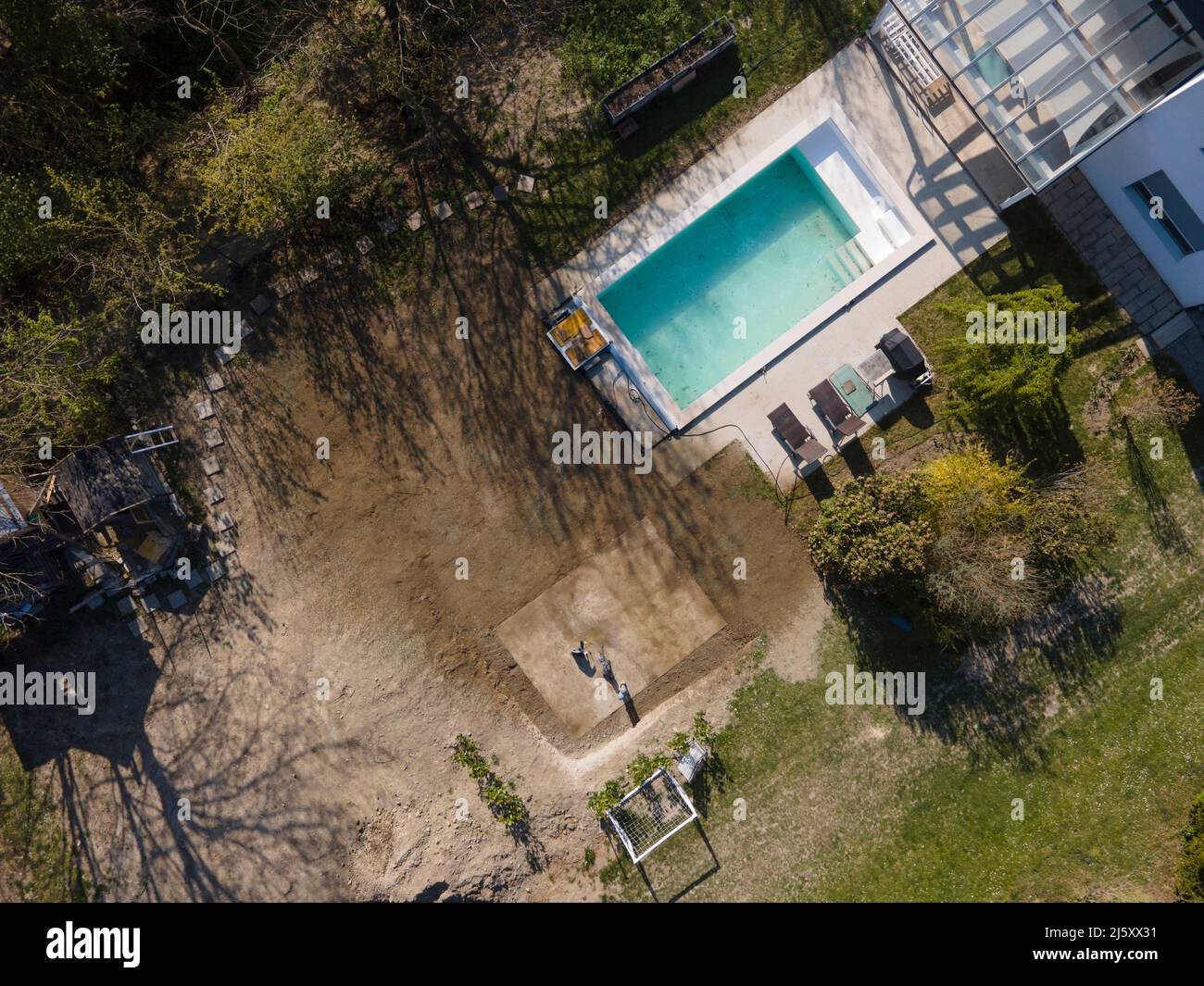 Drone flight over fresh earth area with grass grown next to pool ...