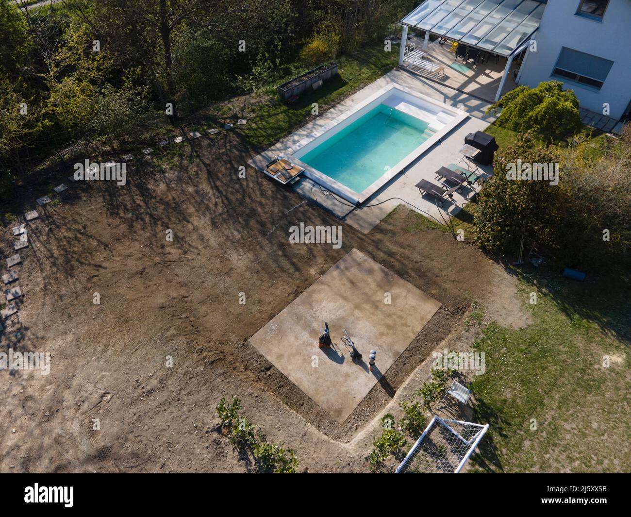 Drone flight over fresh earth area with grass grown next to pool ...