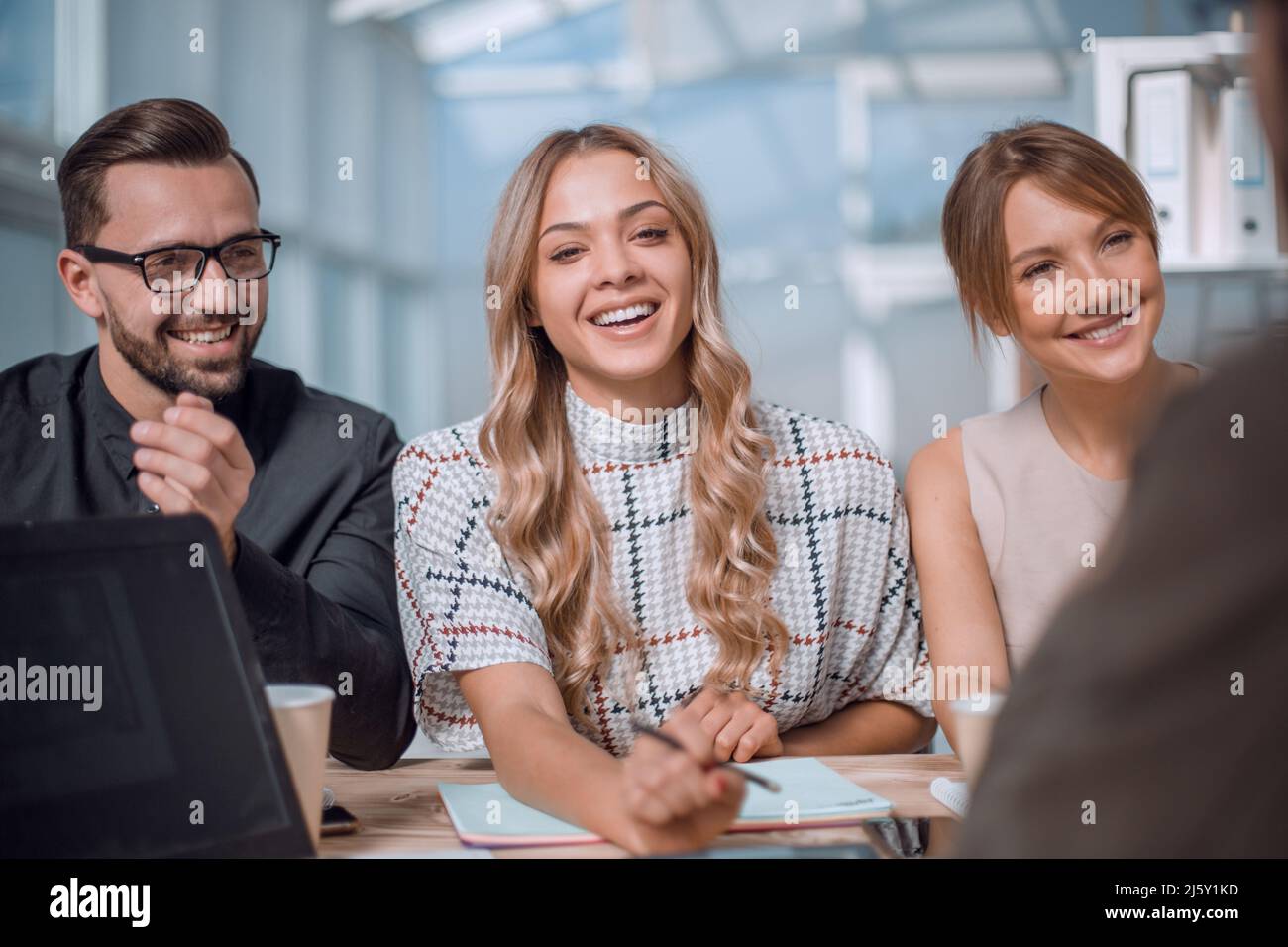 young employee enthusiastically tells something to her colleagues . the ...