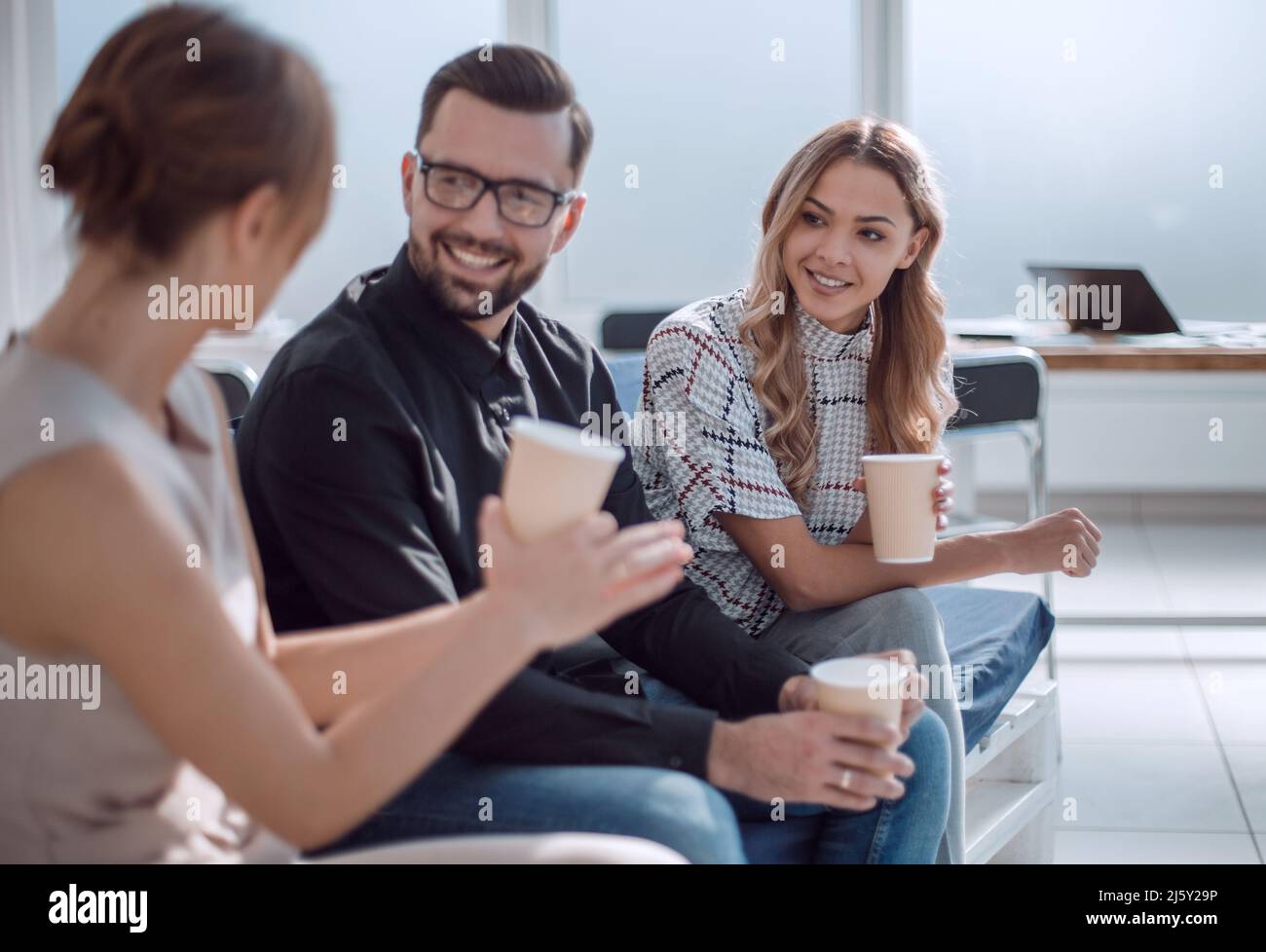 employees of the company with coffee glasses sitting in the office ...