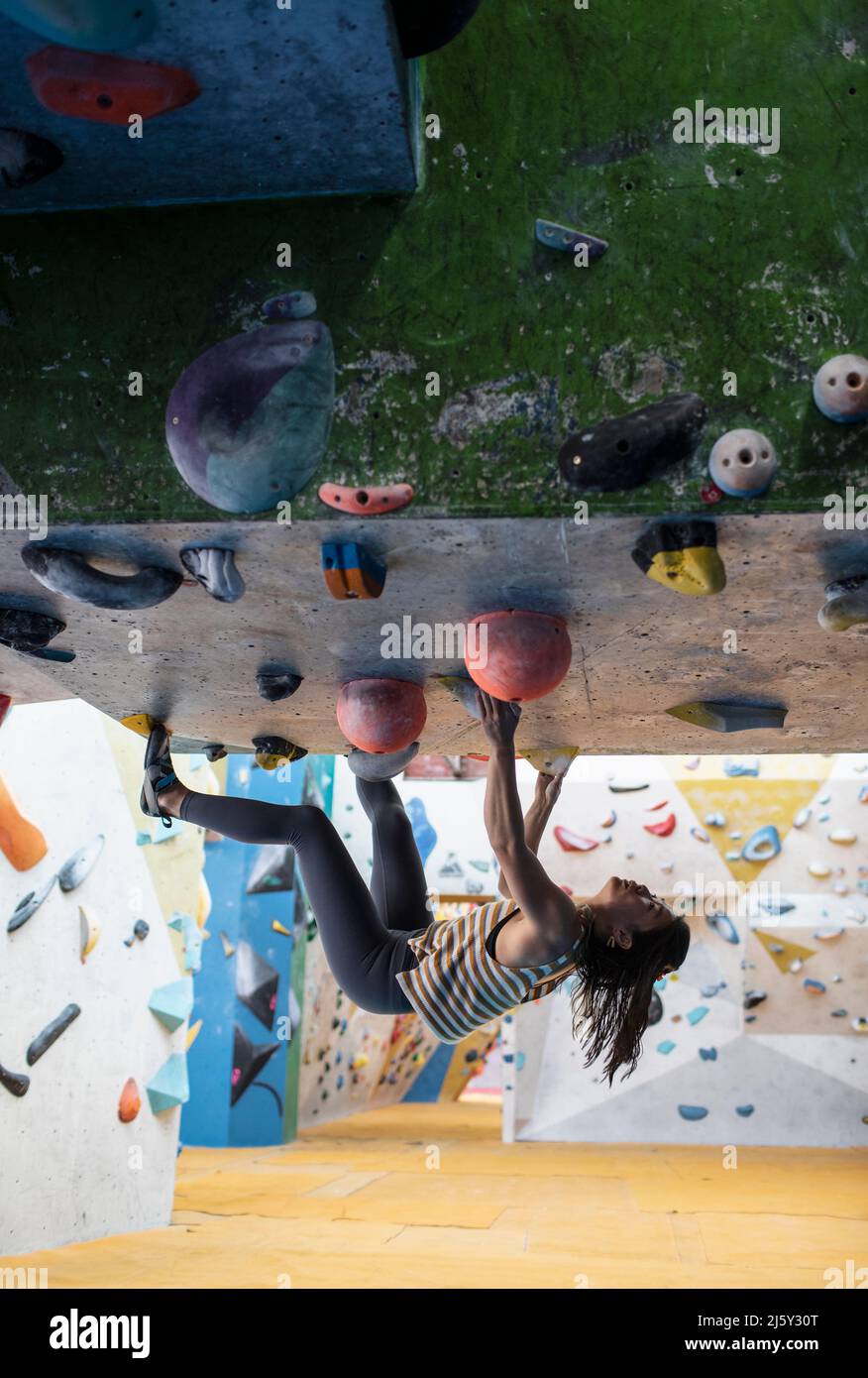Female rock climber hanging upside-down on climbing wall Stock Photo ...