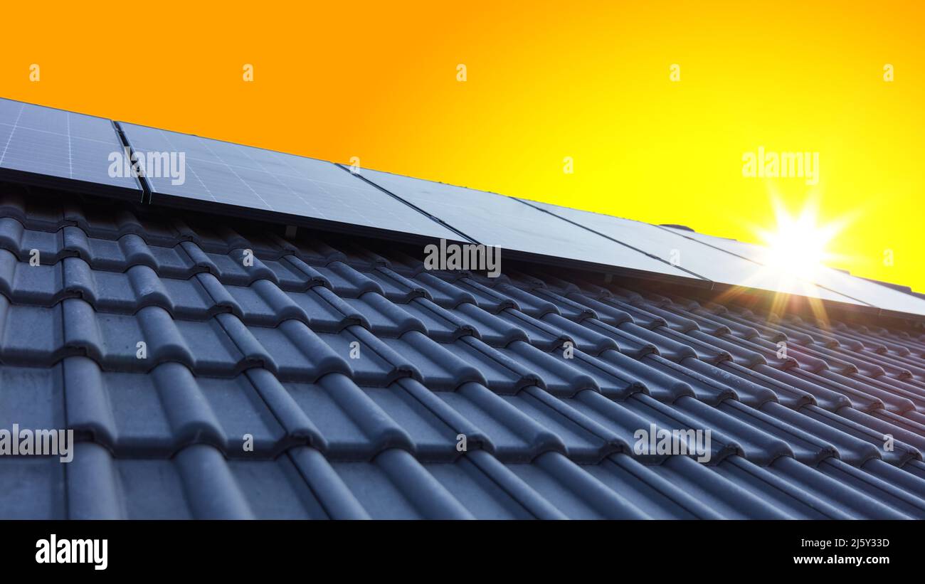 Yellow sun shines brightly on solar panels on roof of a house Stock ...