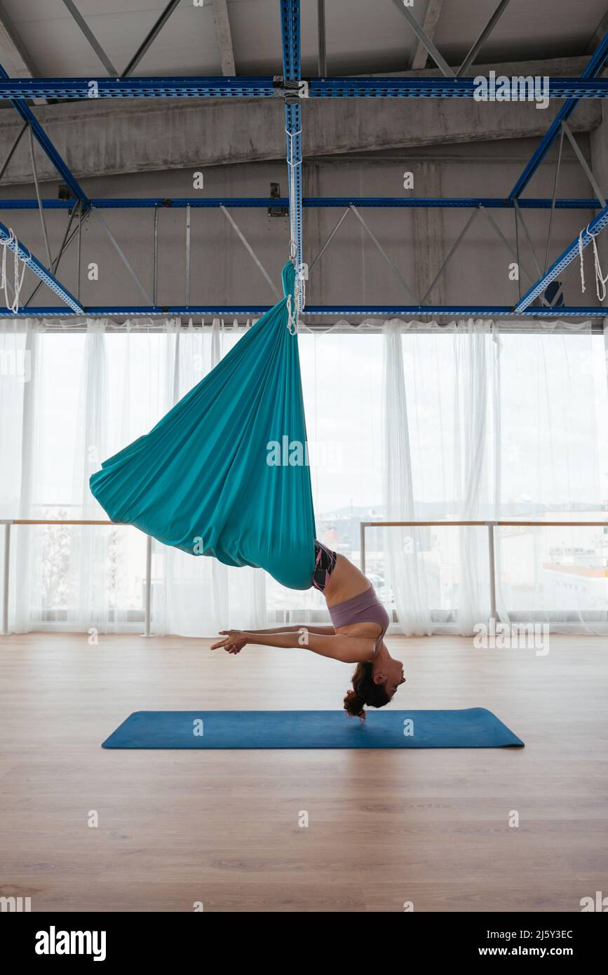 Side view of active female practicing swan dive in hammock during ...