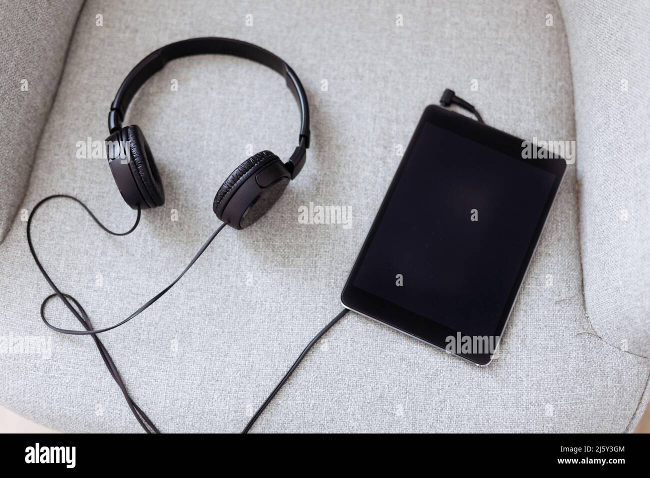 High angle of modern digital tablet with headphones connected by wire ...