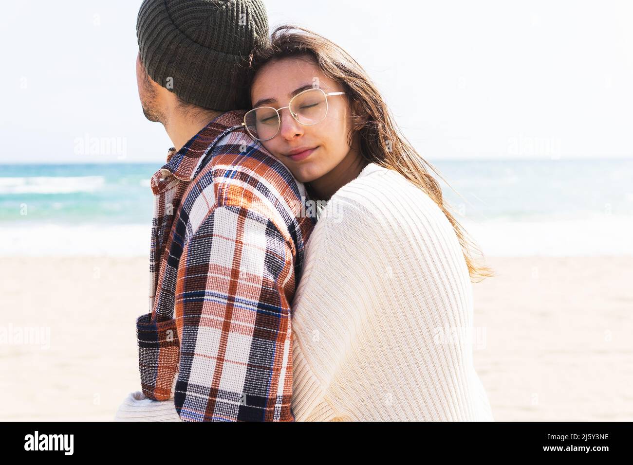 Romantic couple in casual wear cuddling while standing together on ...