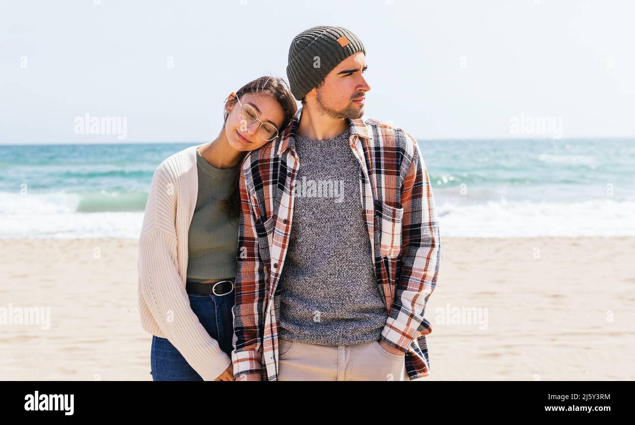Romantic couple in casual wear cuddling while standing together on ...