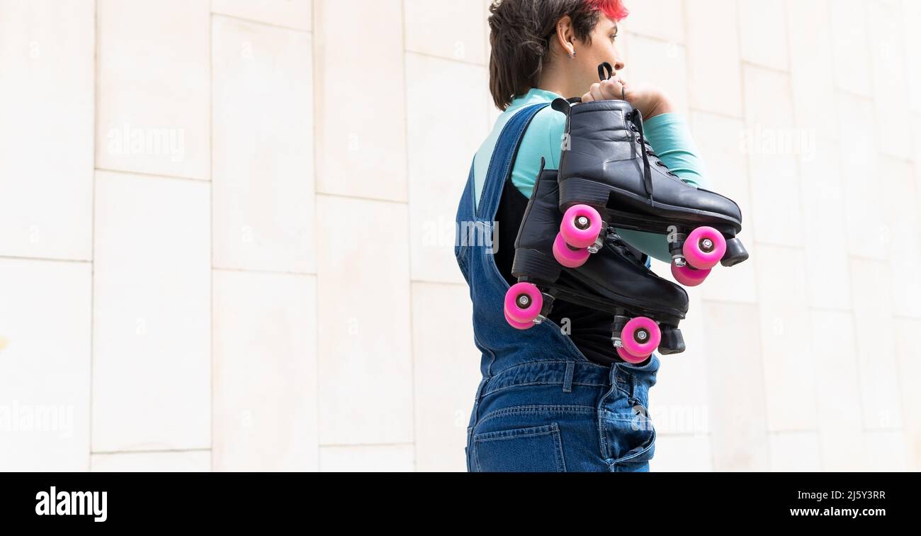 Side view of cropped short haired Woman in denim overall holding roller ...