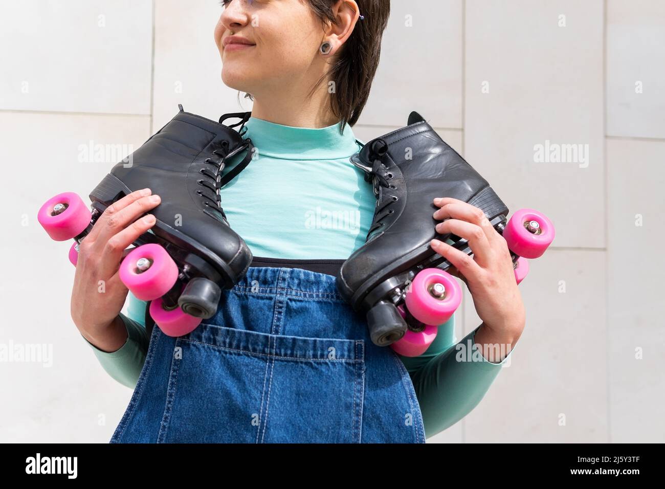Side view of cropped short haired Woman in denim overall holding roller ...