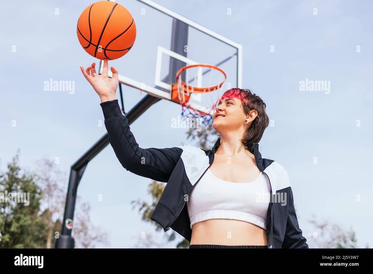Low angle side view of female player throwing ball into hoop while ...