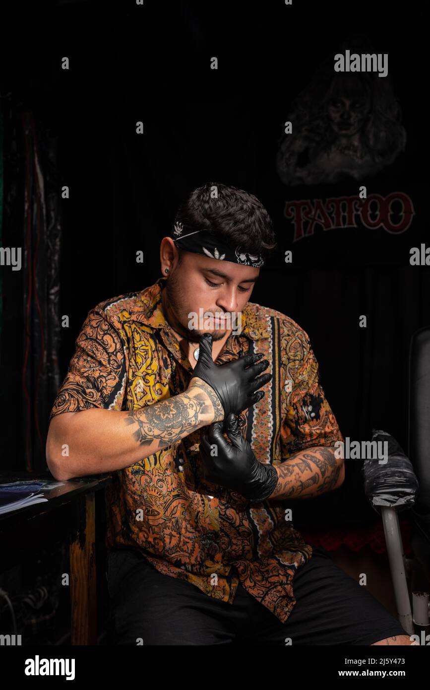 Serious Peruvian male tattoo master in colorful shirt and headband ...