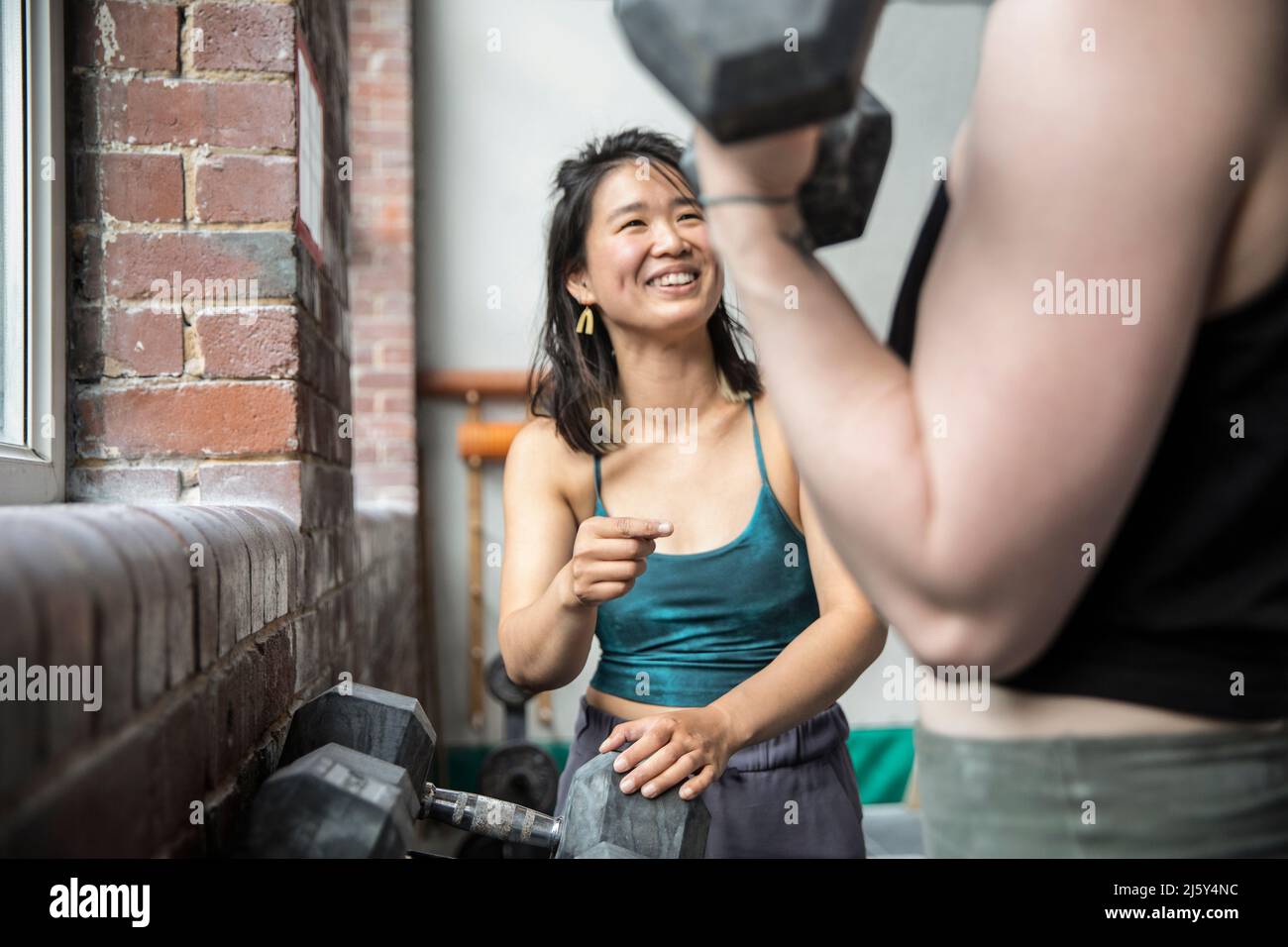 Happy woman working out with friend in gym Stock Photo - Alamy