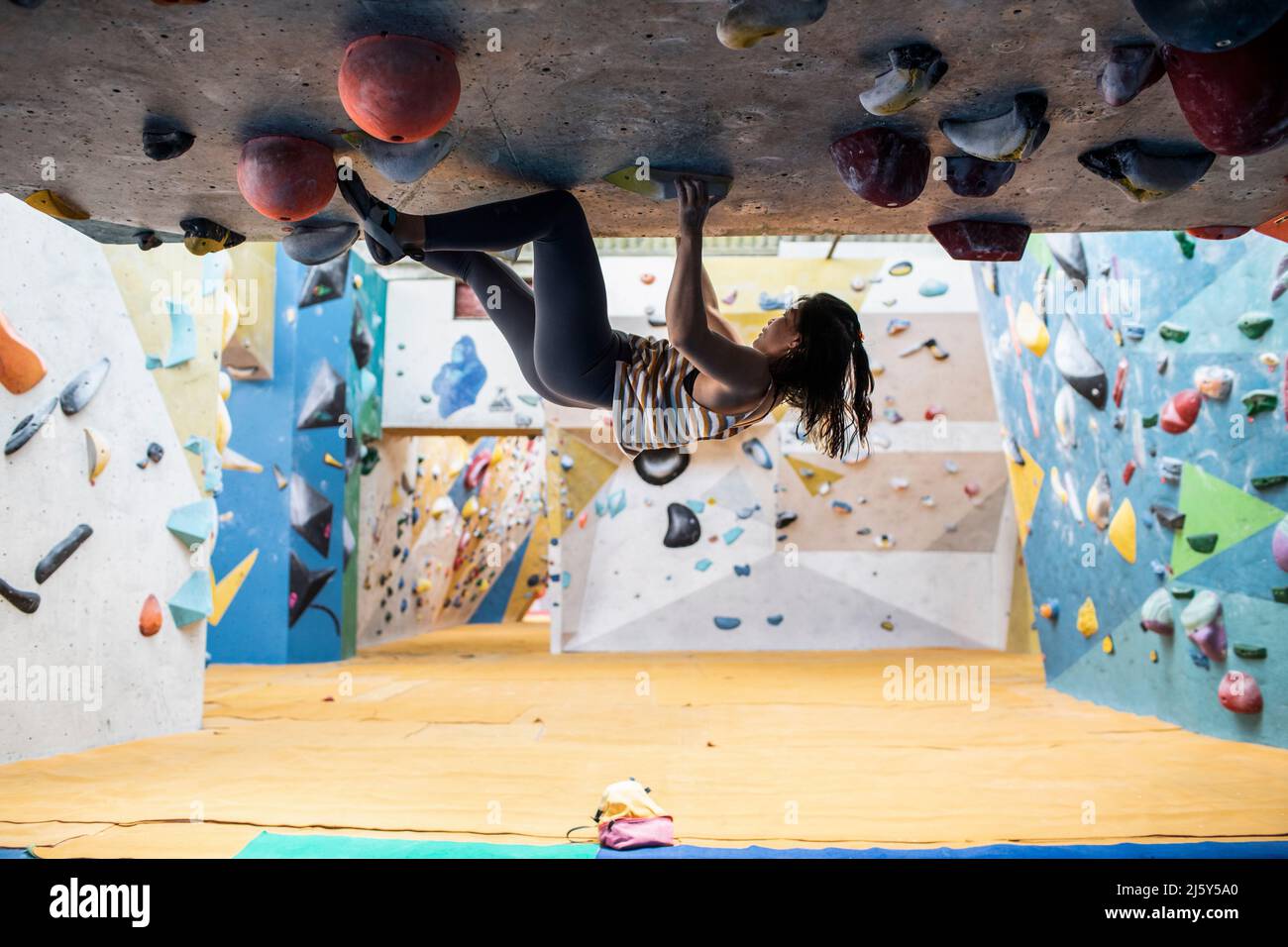 Female rock climber hanging upside-down on climbing wall Stock Photo ...