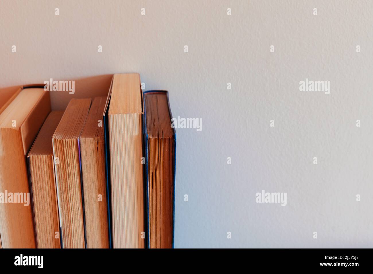Front above books together next to a wall Stock Photo - Alamy