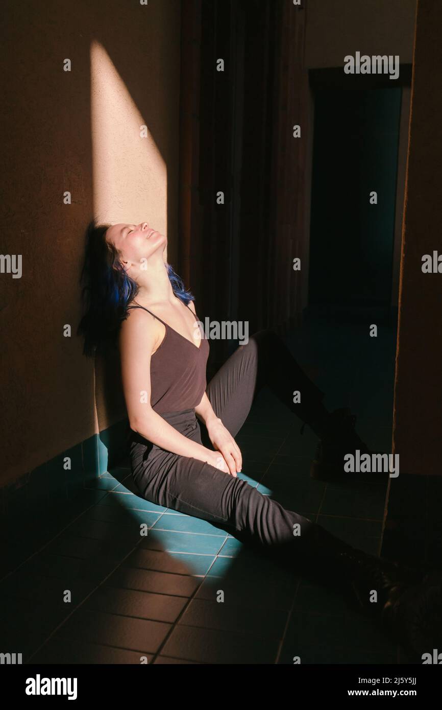 Side view of calm female in black wear sitting with head thrown back at ...