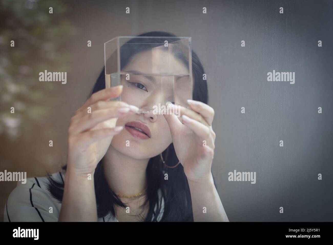 Curious female designer looking at cube with water Stock Photo - Alamy