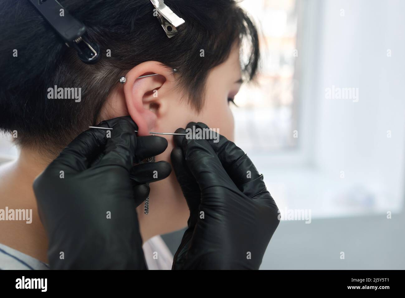 A beautician makes a puncture of the earlobe with a disposable device ...