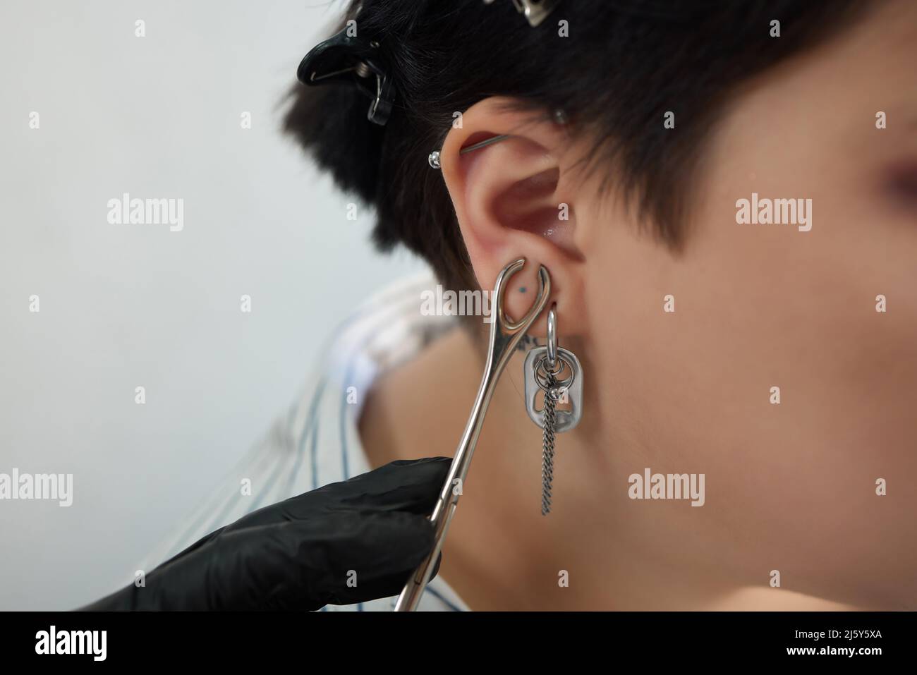 A beautician makes a puncture of the earlobe with a disposable device ...